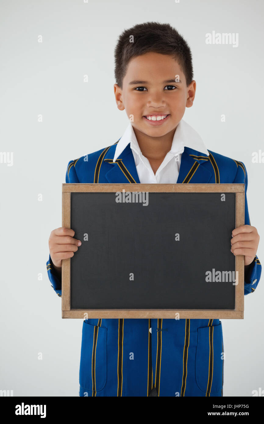 Portrait of schoolboy holding blank writing slate against white ...