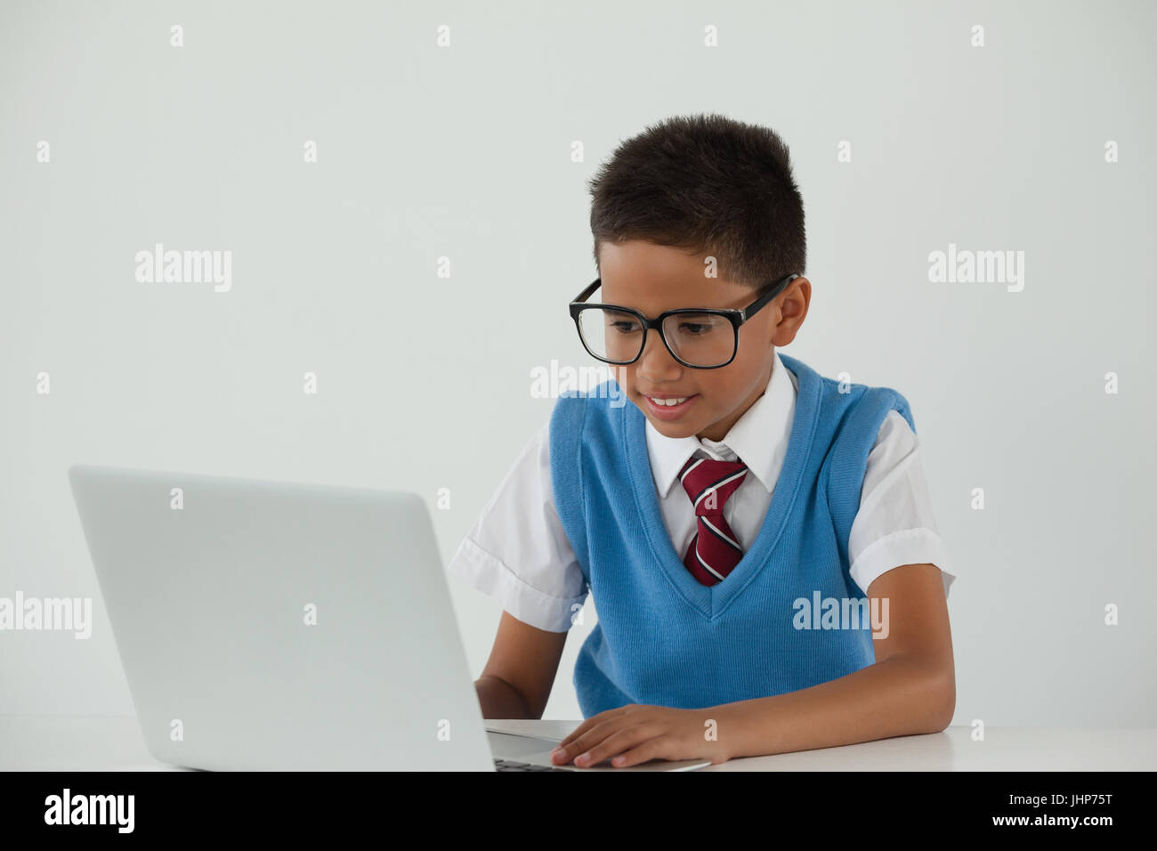 Schoolboy using laptop against white background Stock Photo - Alamy