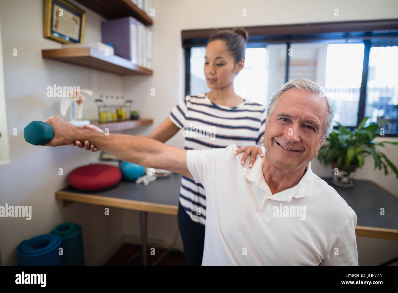 Female doctor holding hand of smiling senior male patient lifting ...