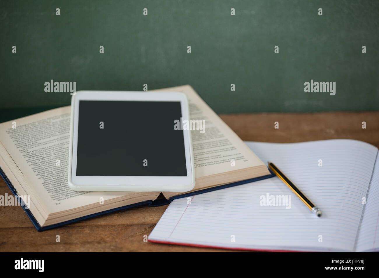 Close-up of digital tablet and books on table in classroom at school ...