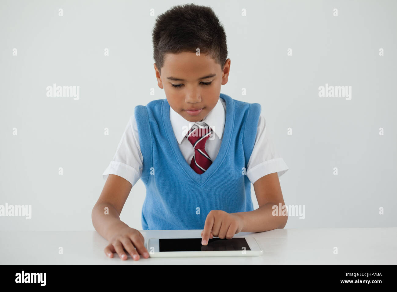 Schoolboy using digital tablet against white background Stock Photo - Alamy