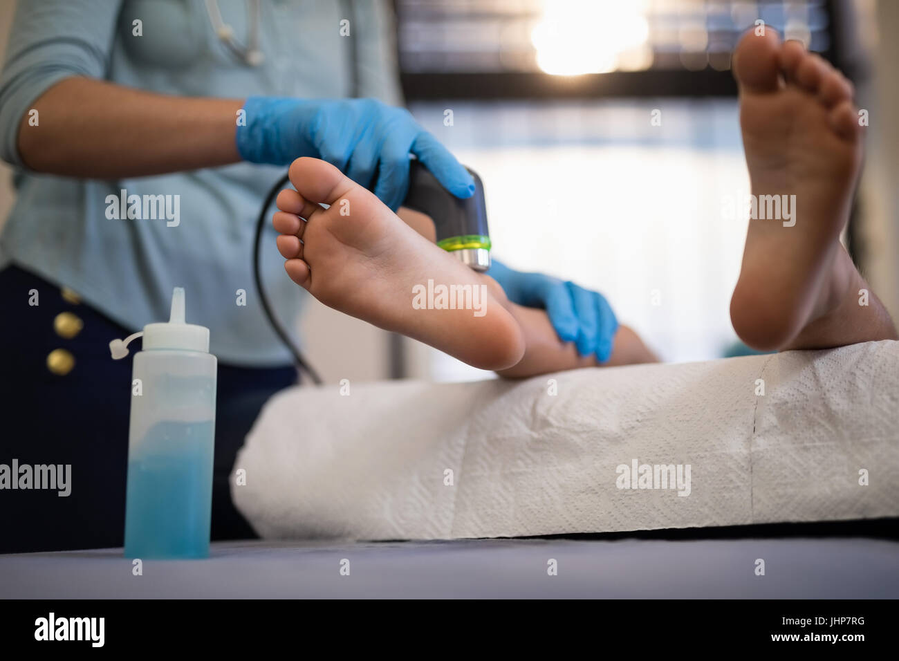 Low section of boy receiving ultrasound scan on feet from female ...