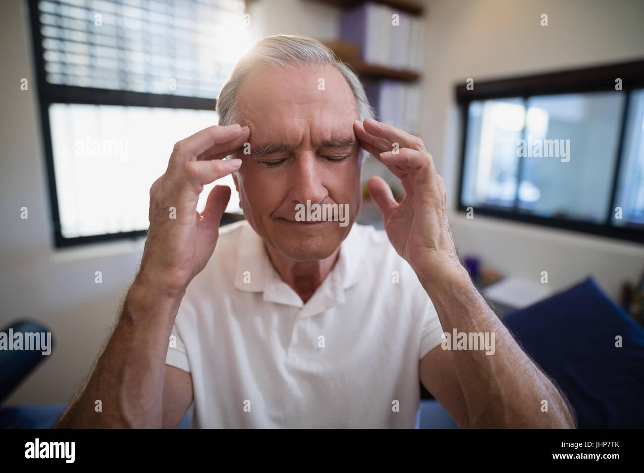 Senior male patient holding head during headache at hospital Stock ...