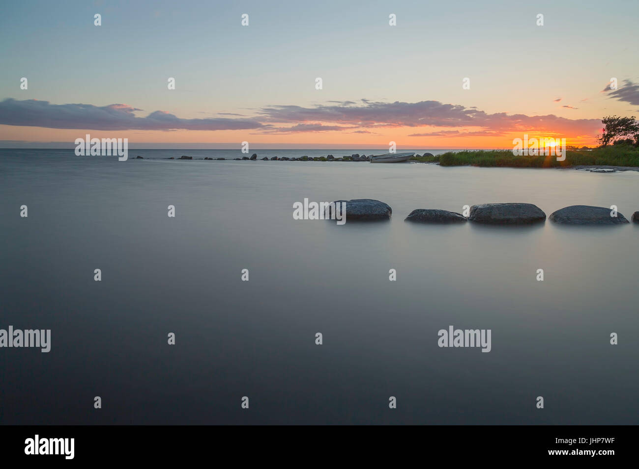 Sunset over Ocean with Breakwater and rowboat in Gotland, Sweden Stock ...