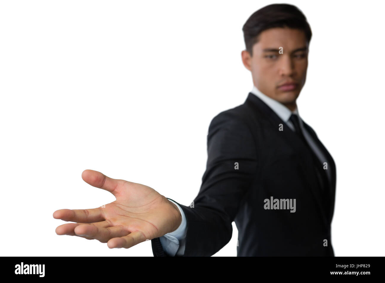 Side view of young businessman looking at hand while standing against ...