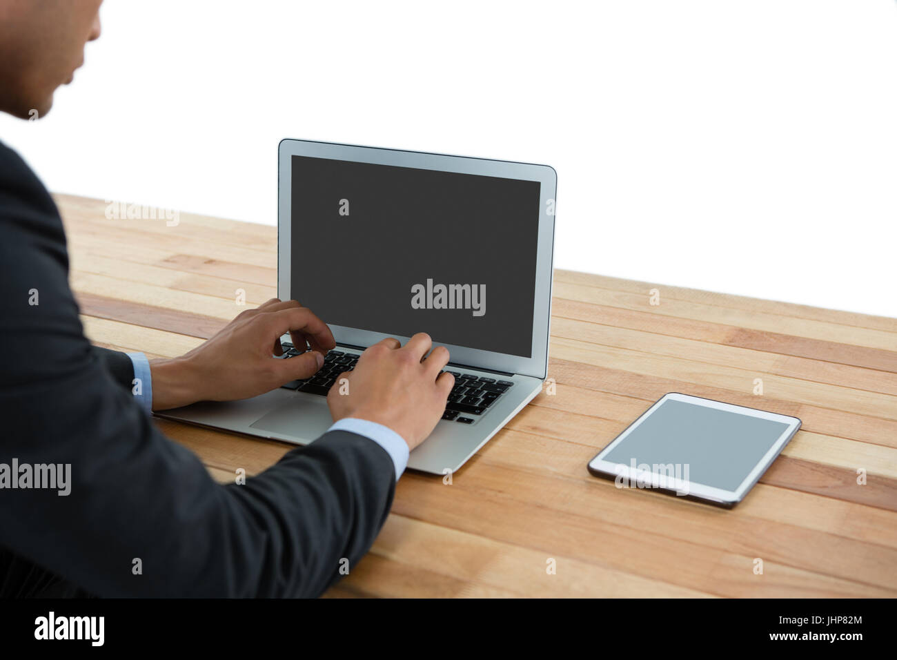 Side view of businessman using laptop computer at table against white ...