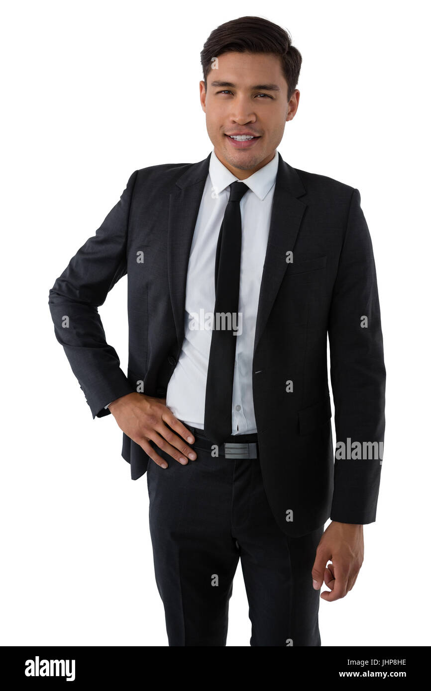 Portrait of smiling young businessman with hand on hip standing against white background Stock ...