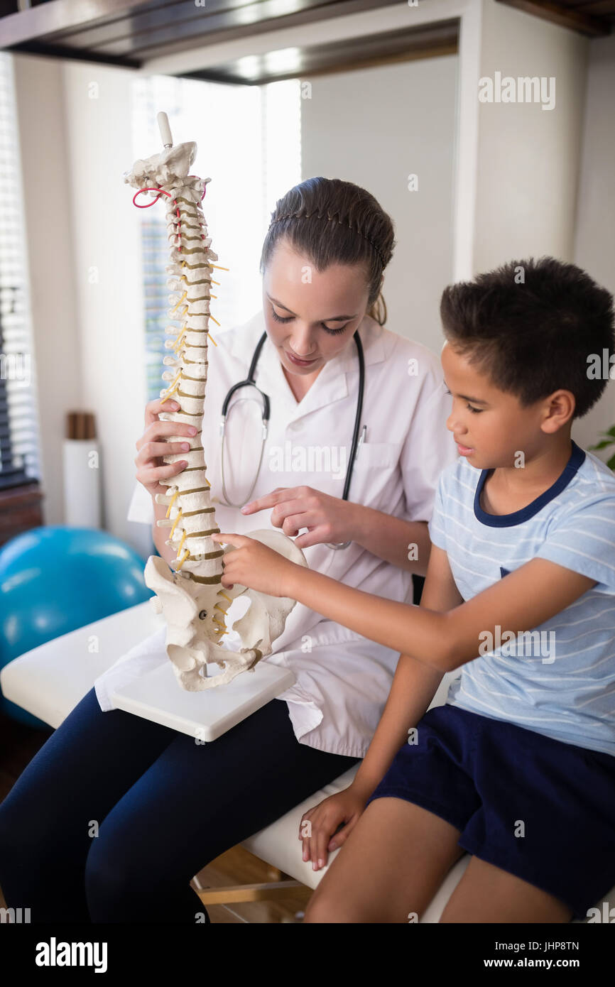 Boy touching artificial bone held by female therapist at hospital ward ...