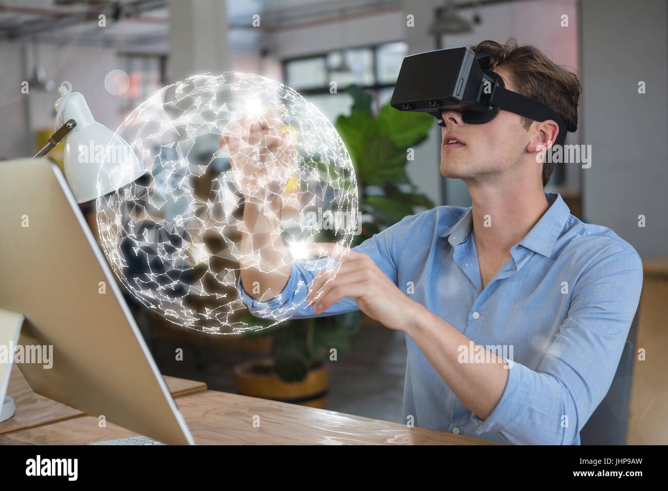 Digital composite of Man in VR headset touching a 3D sphere interface ...