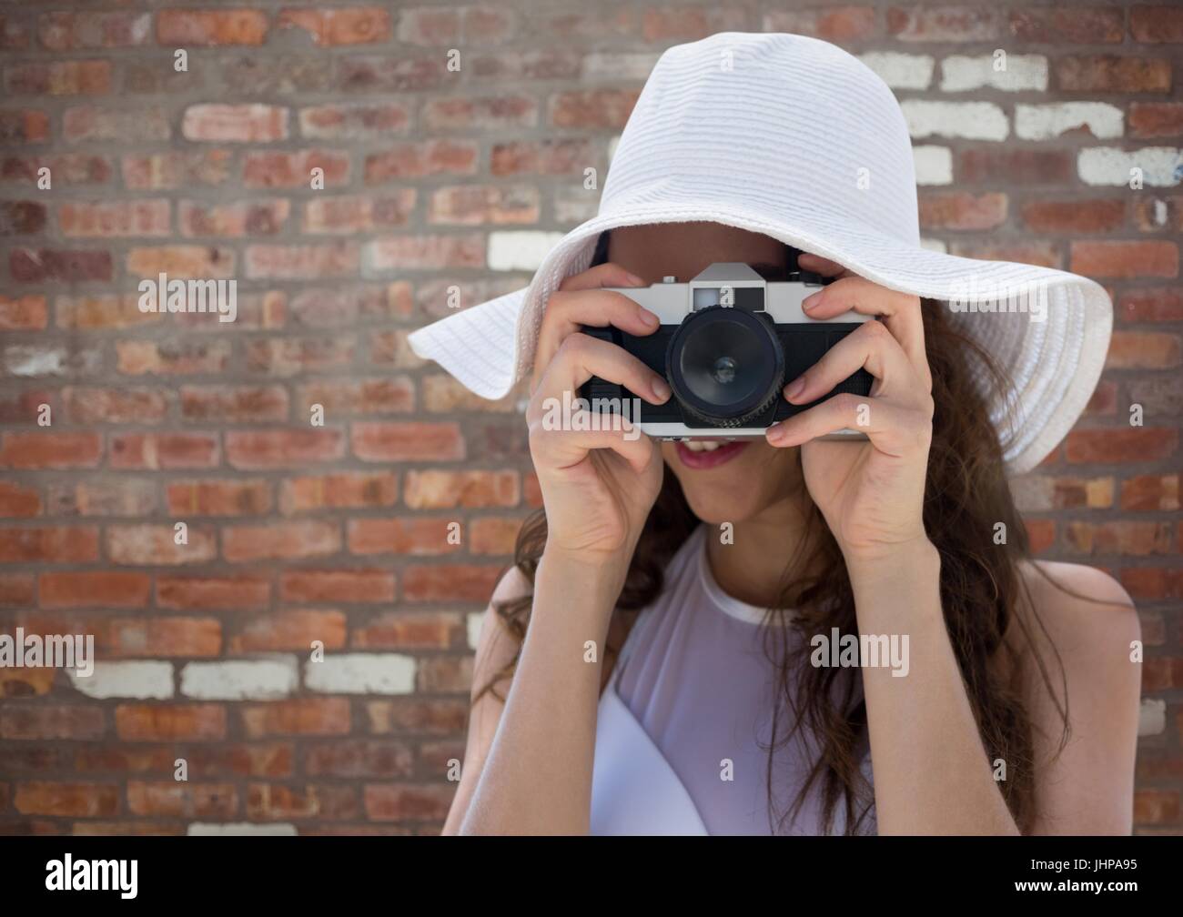 Digital composite of Millennial woman in summer hat with camera against ...