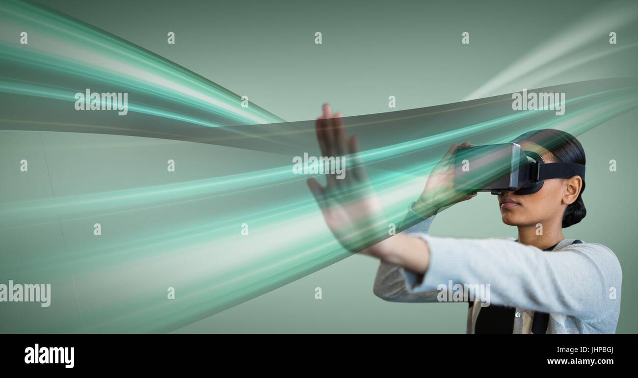 Digital composite of Woman in VR headset touching green light against ...