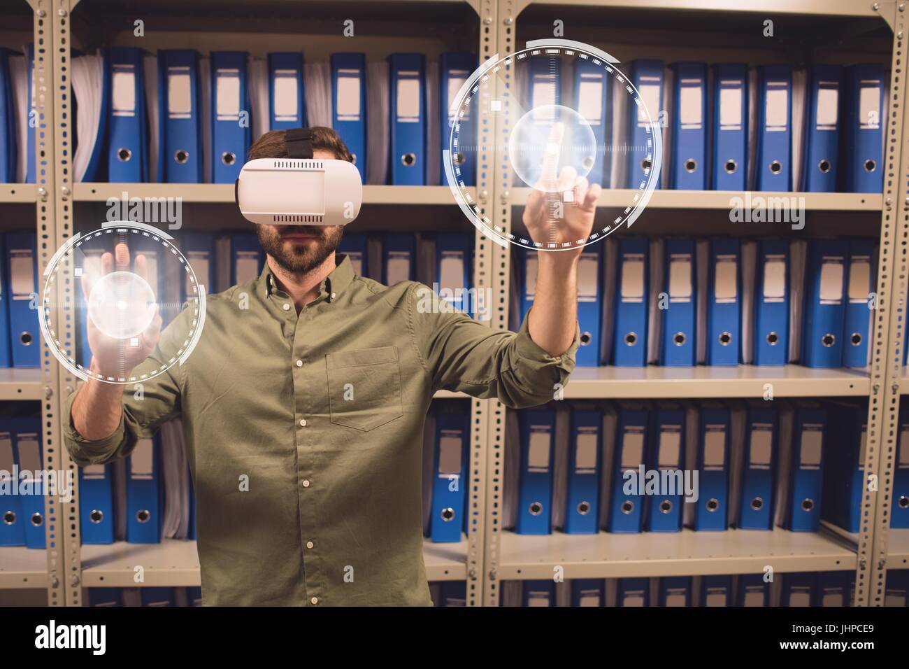 Digital composite of Man in VR headset touching interfaces with flares ...