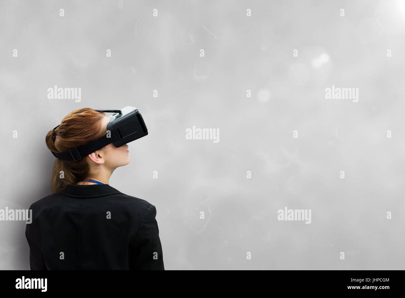 Digital composite of Woman in VR headset looking up against grey ...