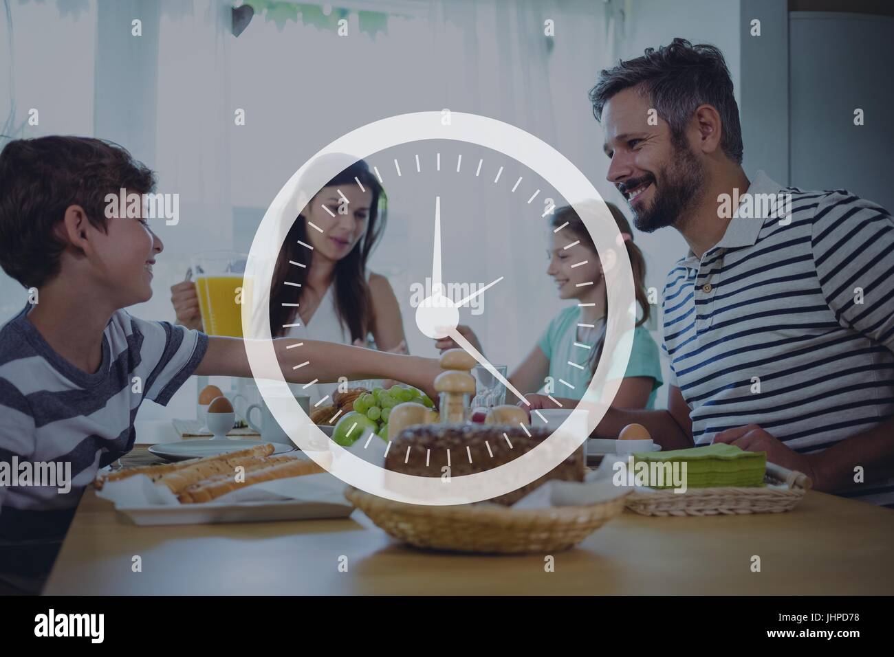 Digital composite of Clock icon against family having dinner photo ...