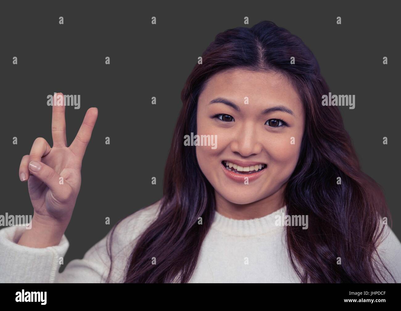 Digital composite of Portrait of woman making peace sign with grey ...