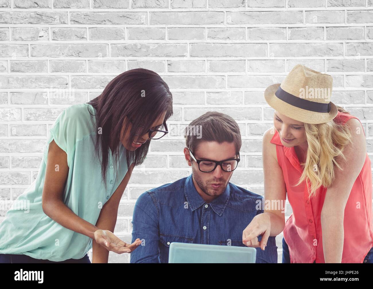 Digital composite of Group of people on laptop in front of brick ...
