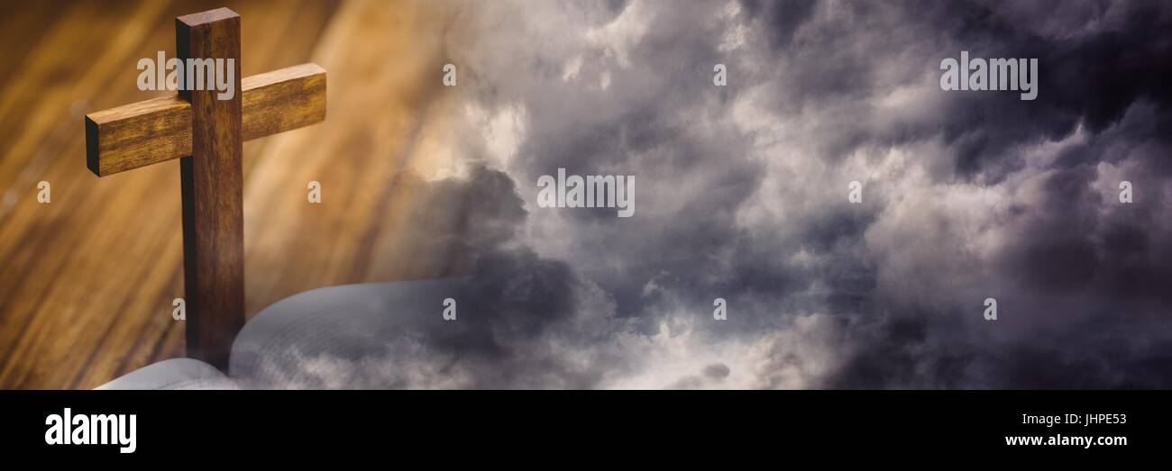Digital composite of Standing cross on bible and storm cloud transition ...