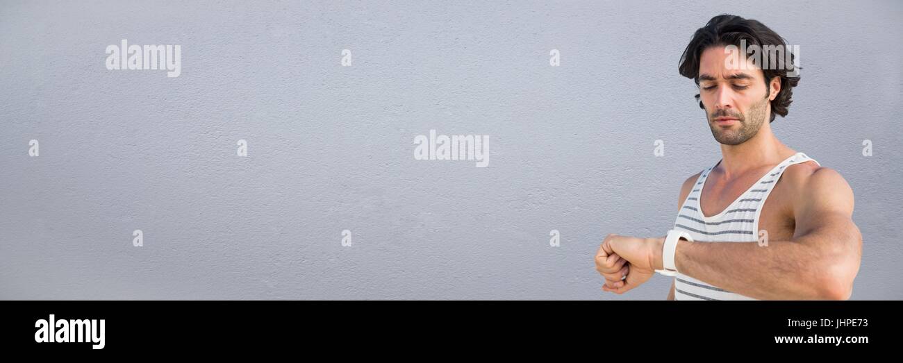 Digital composite of Man training looking at watch against grey wall ...