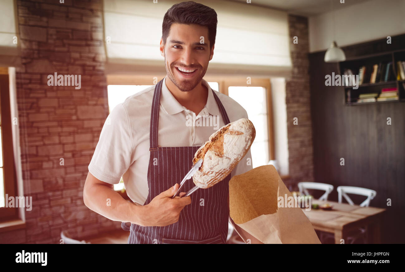 Baker packing loaf of bread against empty chairs and tables Stock Photo ...