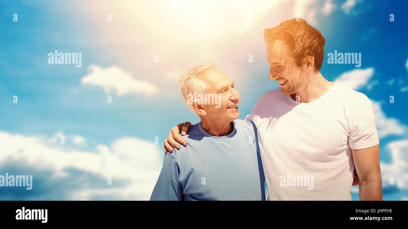 Adult son hugging his old father against cloudy sky with sunshine Stock ...