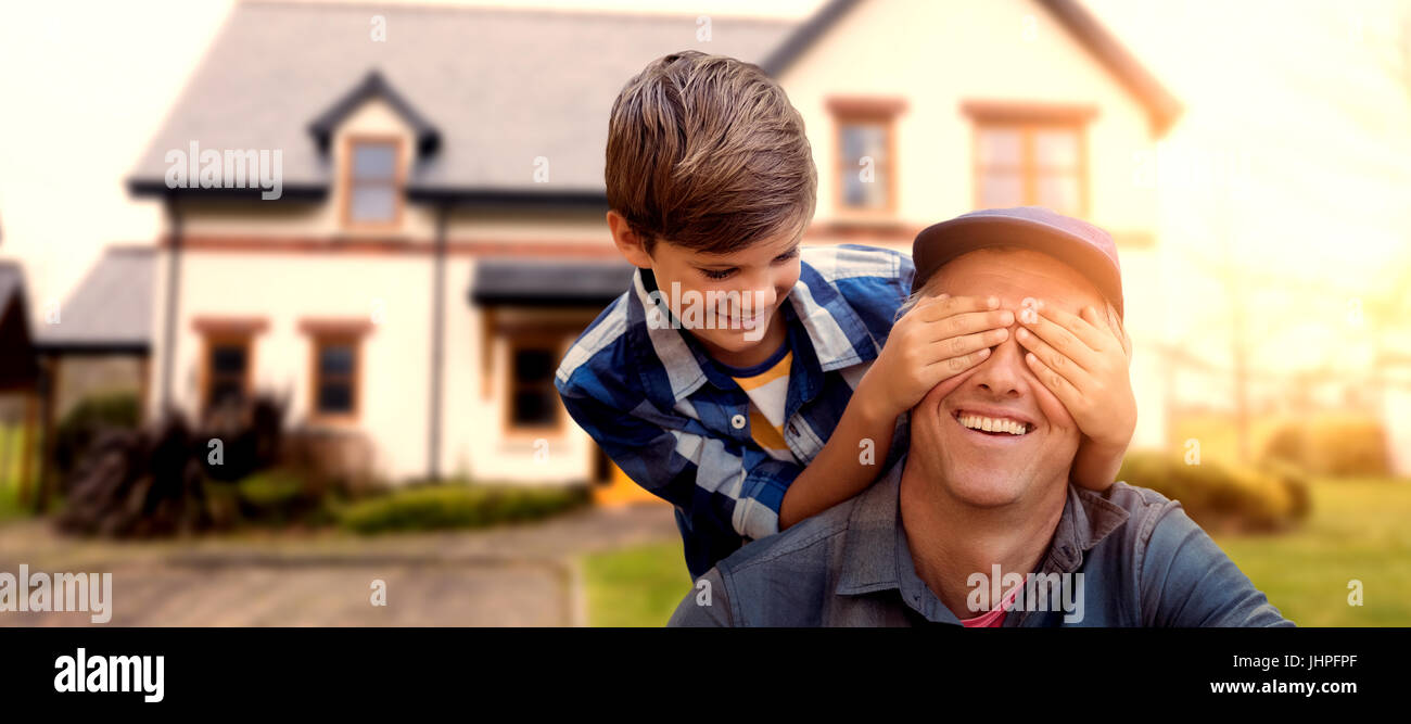 Little boy hiding his fathers eyes with his hands against facade of ...