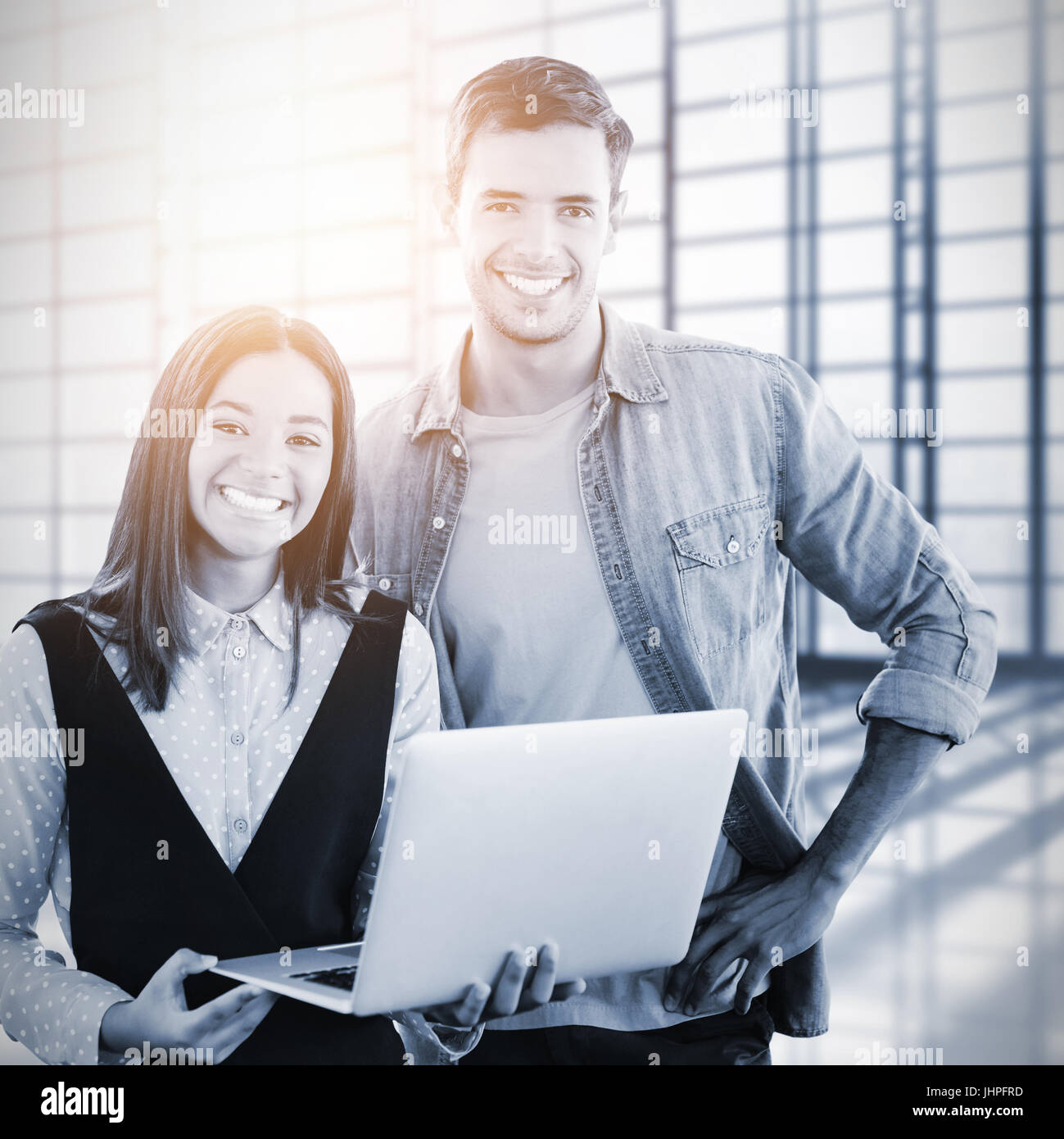 Smiling teamwork looking at camera against room with large window ...