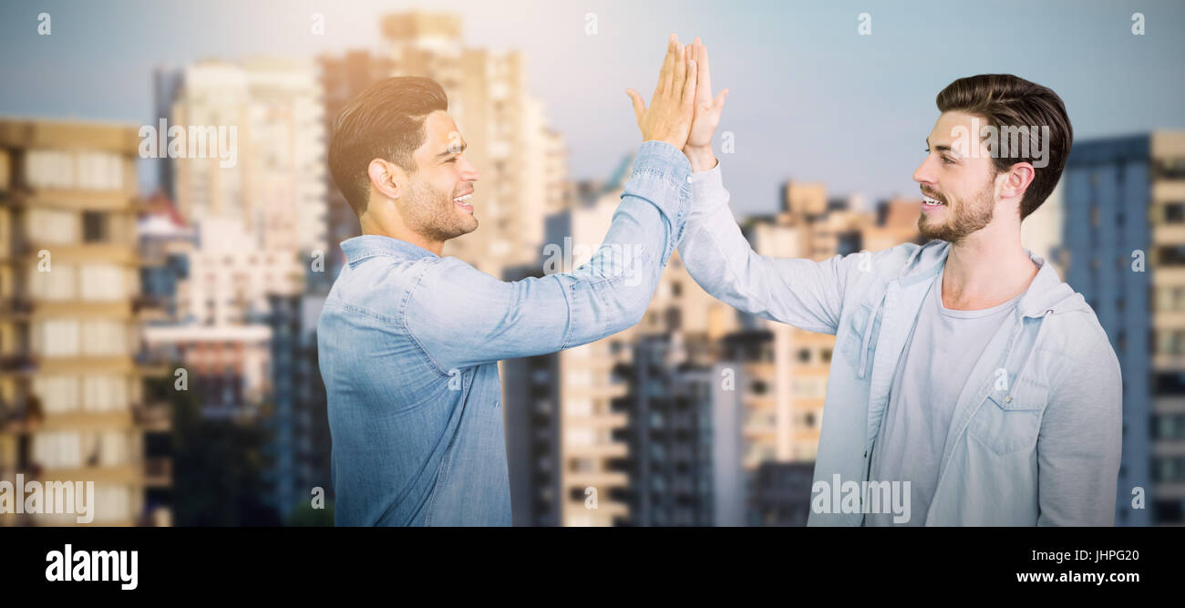 Smiling boys clapping his hands against sunlight falling on buildings ...