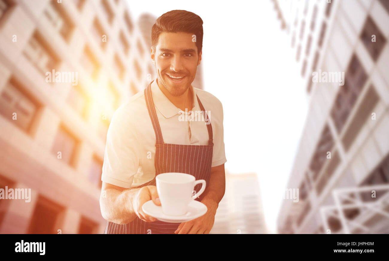 Waiter pointing a cup of coffee against low angle view of office towers ...