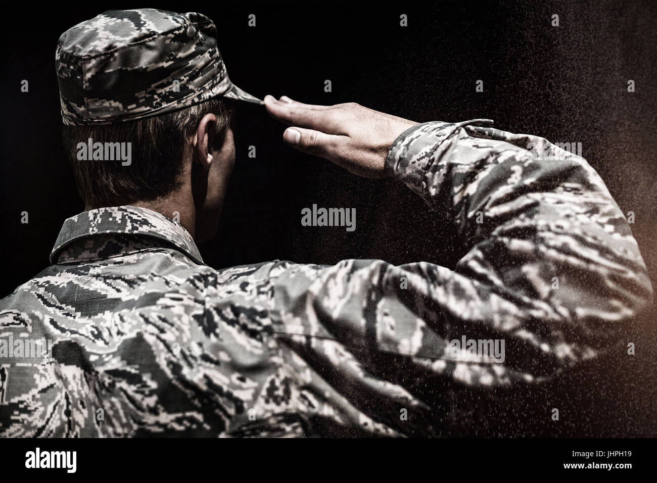 Black background against rear view of a military soldier saluting Stock ...