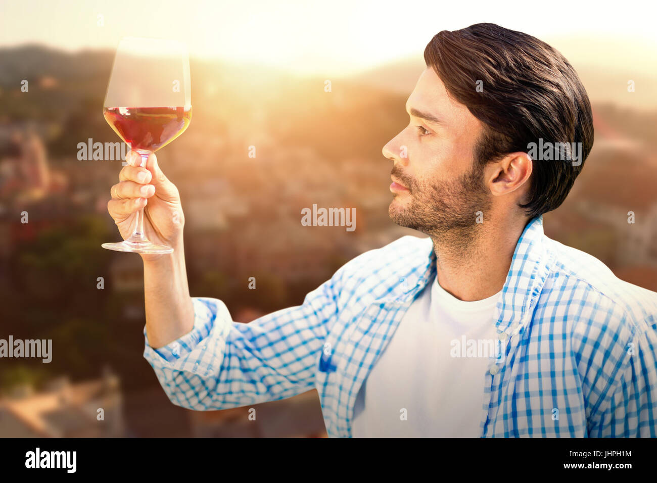Man looking at glass of red wine against city landscape Stock Photo - Alamy