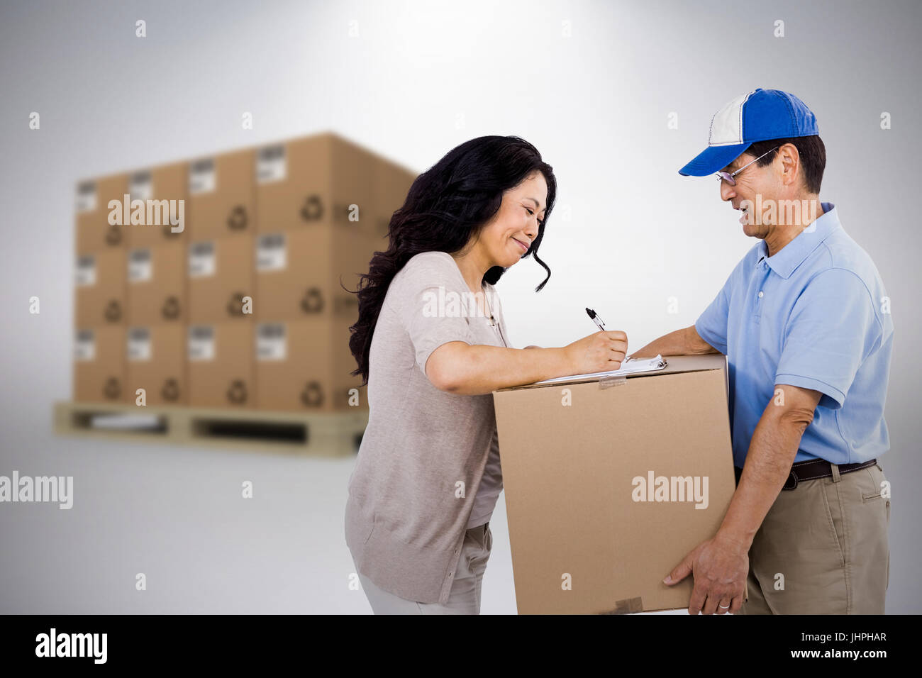 Woman signing for a package against grey background Stock Photo - Alamy