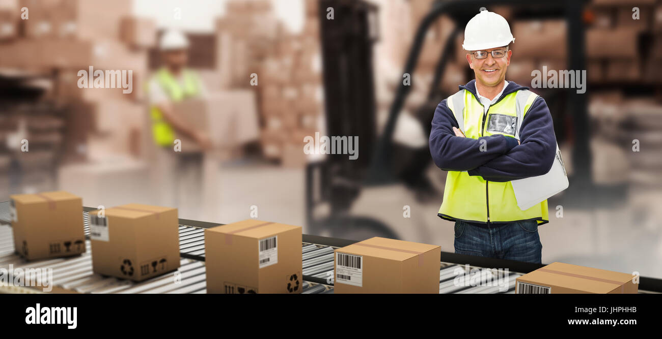 Worker wearing hard hat in warehouse against warehouse worker loading ...