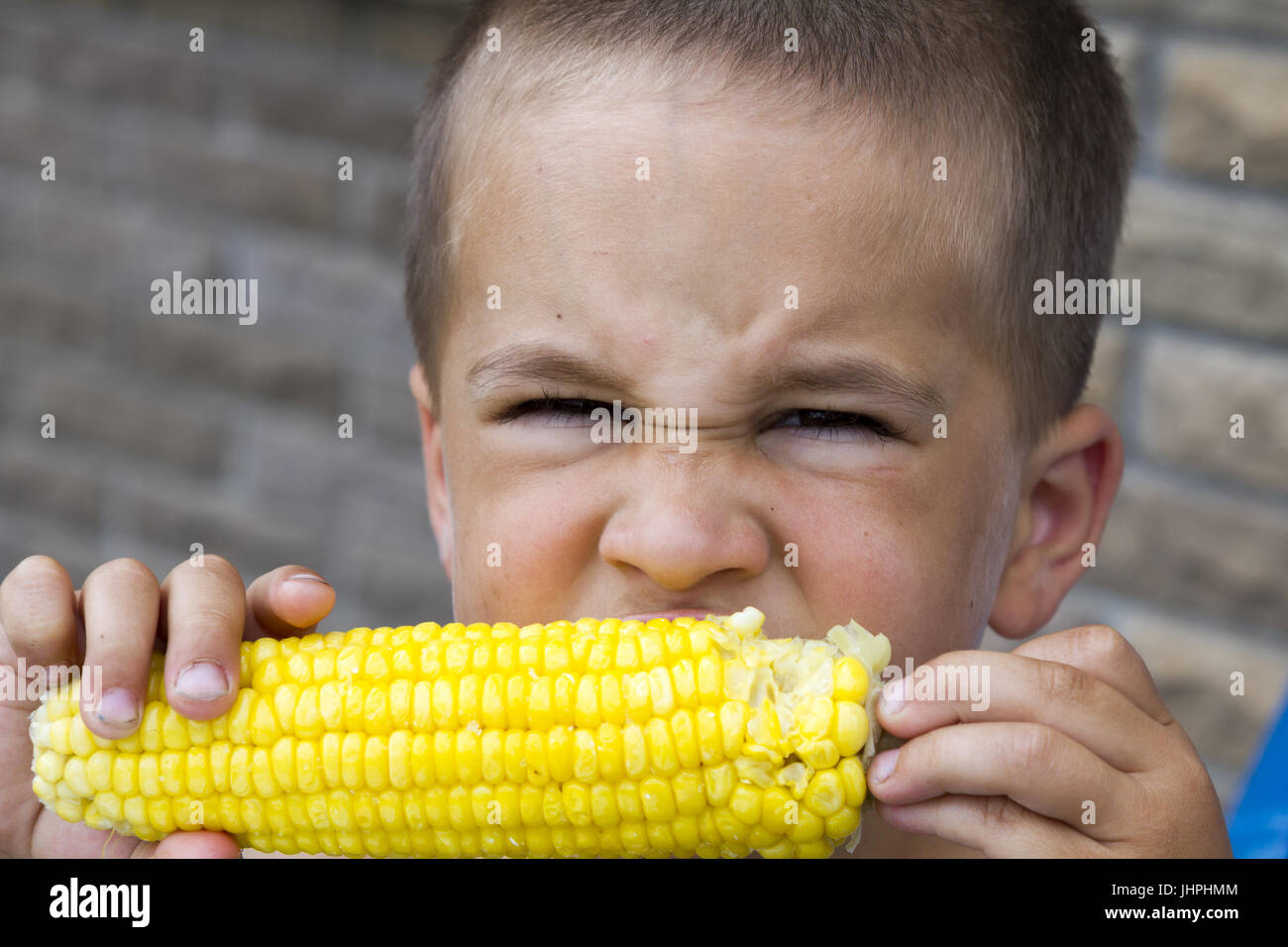 Happy boy eating corn on the cob Stock Photo - Alamy