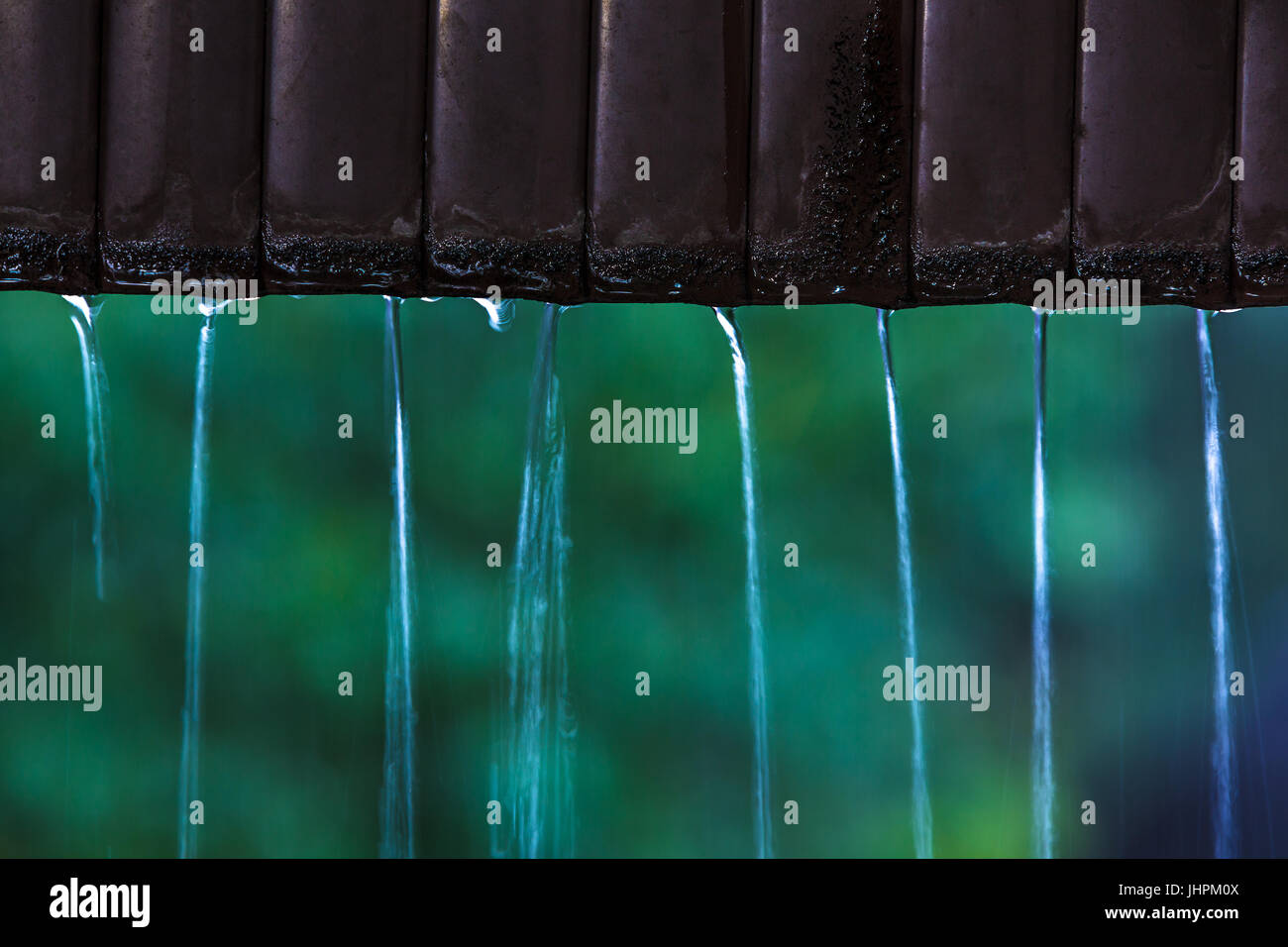 blurred streaks of rain coming down from rusted metal roof with blurred ...