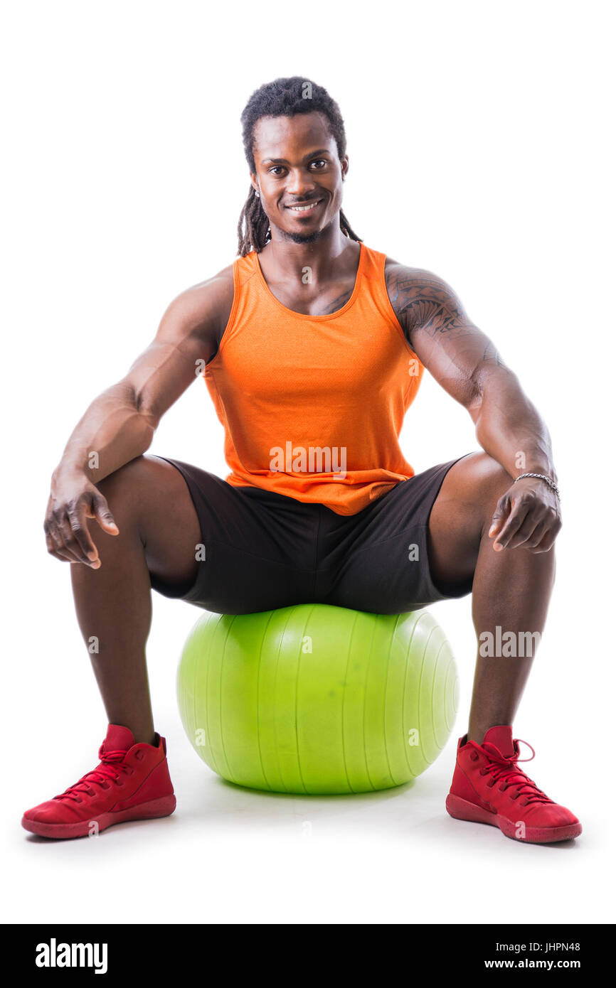 Muscular black man sitting on inflatable fitness ball, looking at ...