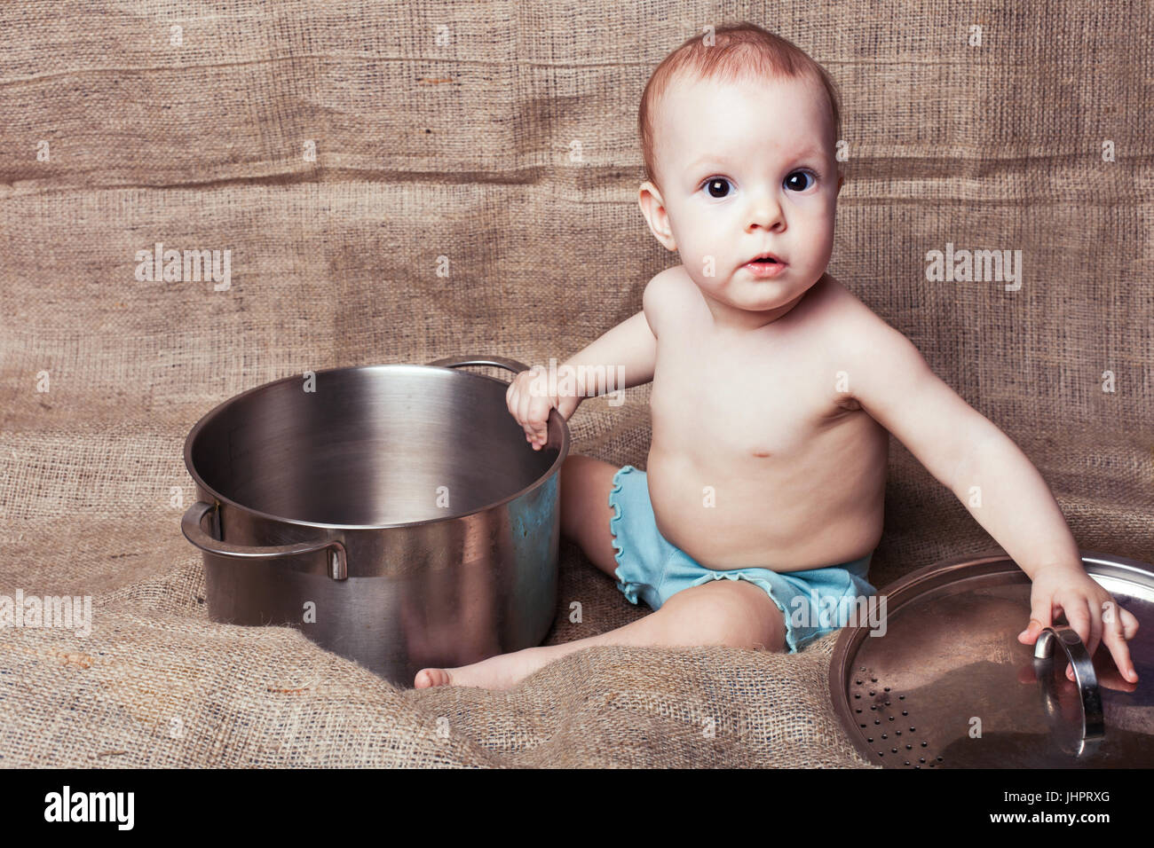Child girl sits and exploring a pan with surprise Stock Photo - Alamy