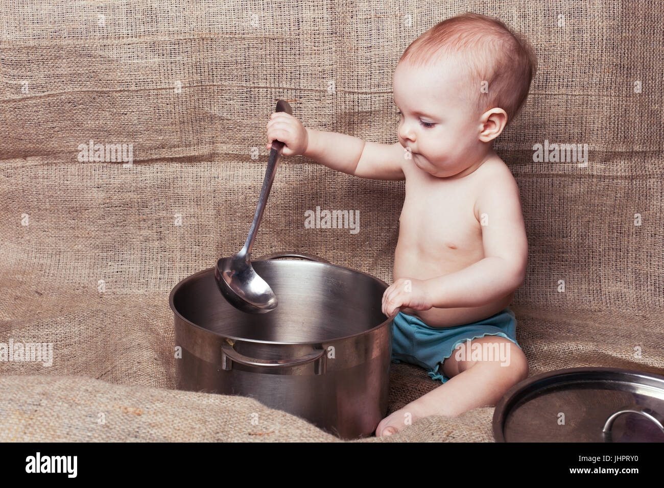 Little girl sits and plays with a pan and ladle Stock Photo - Alamy