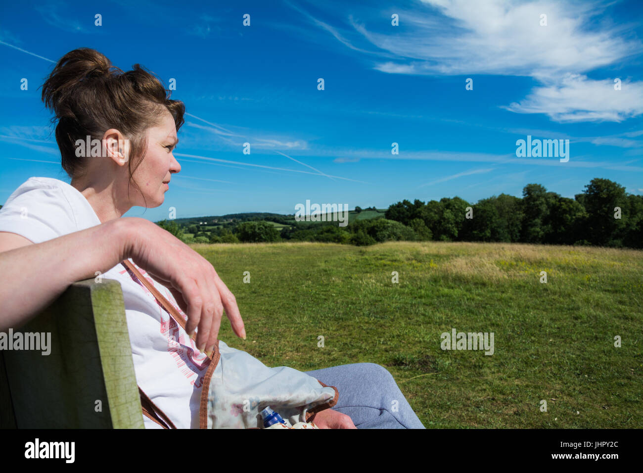 Pretty middle aged woman sat enjoying the sun. Summer, UK Stock Photo ...