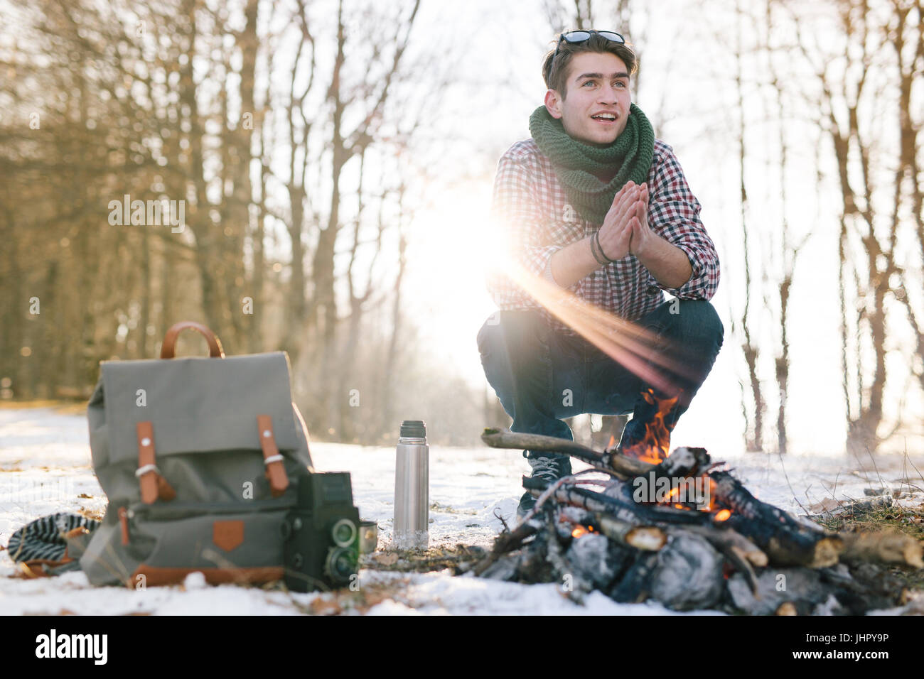Handsome caucasian scout man warming his hands from bonfire in the ...