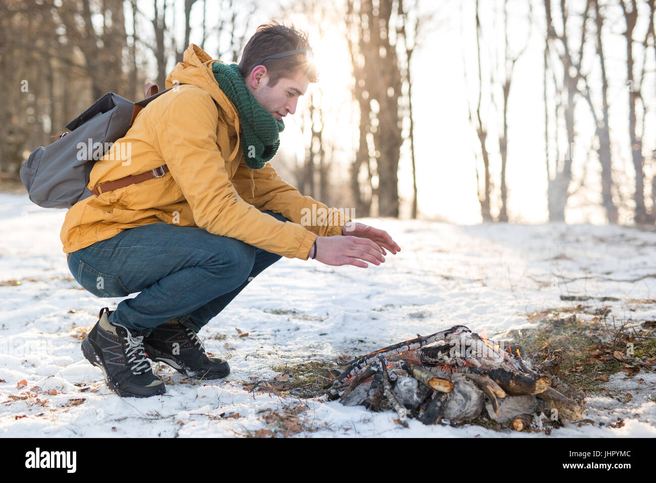 Handsome caucasian scout man warming his hands from bonfire in the ...