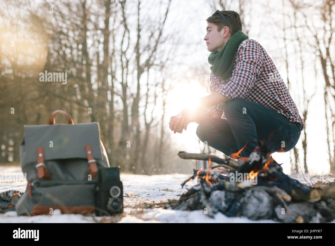 Handsome caucasian scout man warming his hands from bonfire in the ...