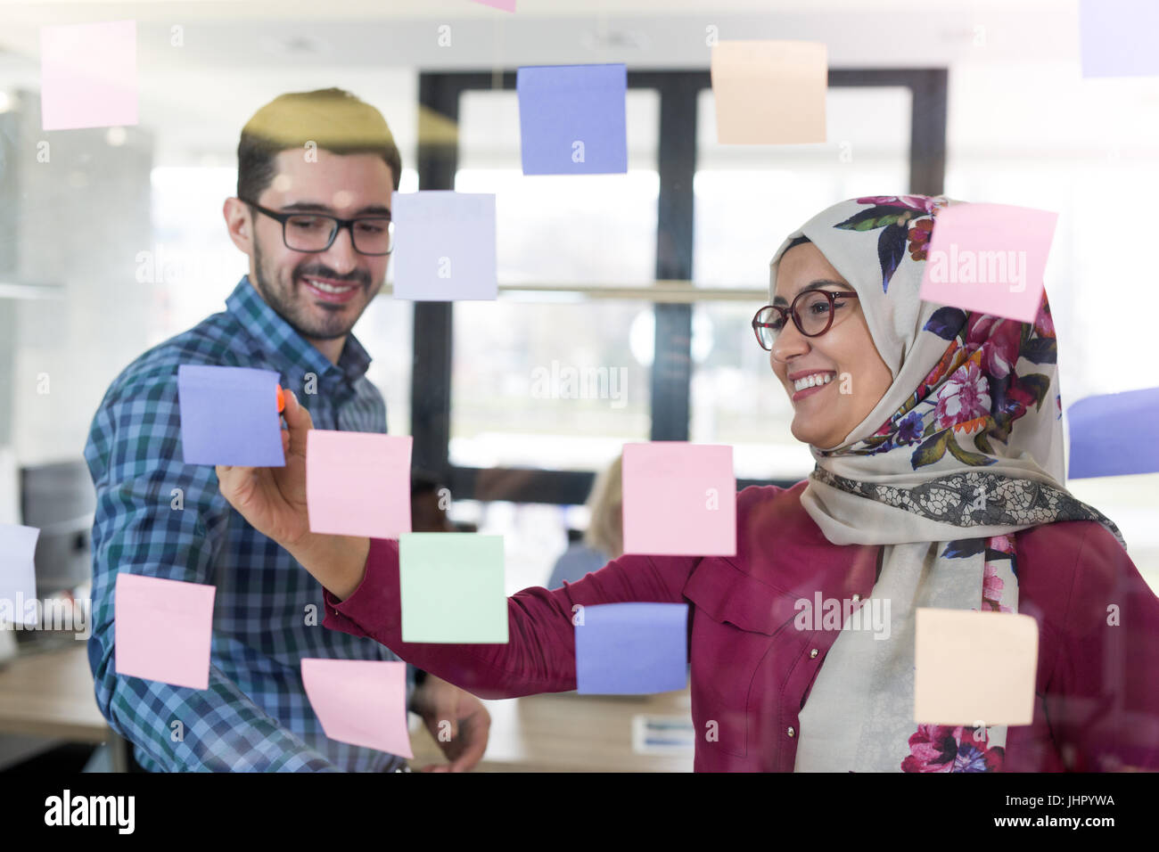 Smiling modern partners looking at sticky notes Stock Photo - Alamy