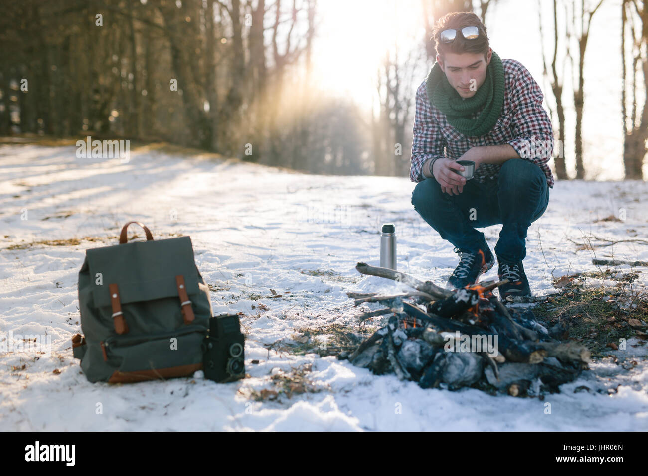 Handsome caucasian scout man warming his hands from bonfire in the ...