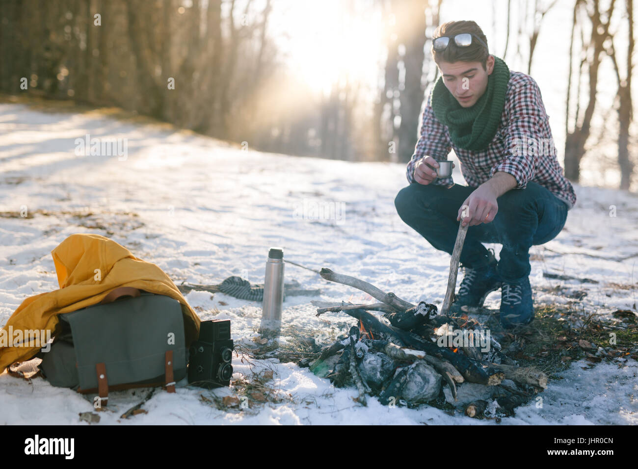 Handsome caucasian scout man warming his hands from bonfire in the ...
