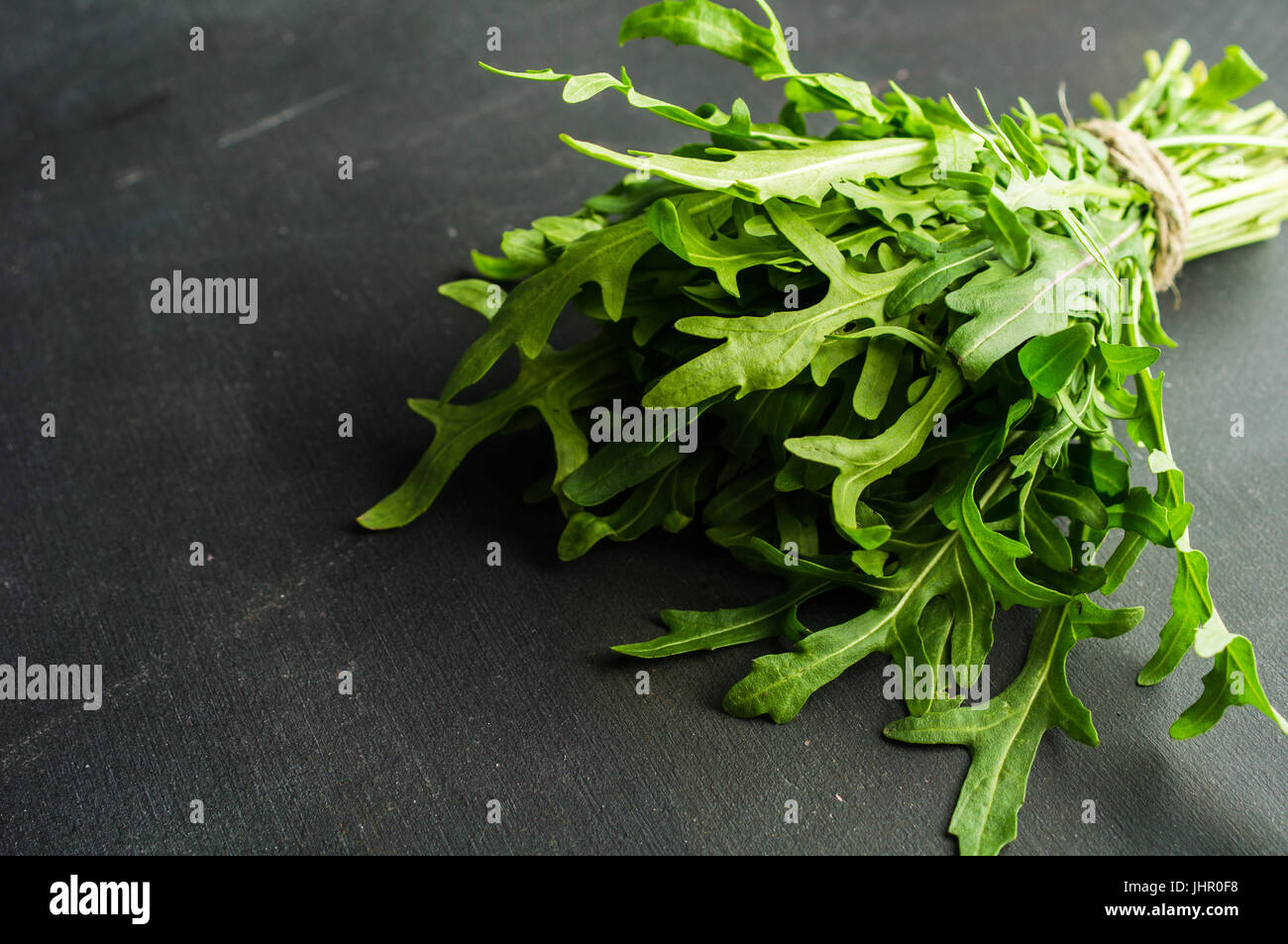Organic food concept with fresh leaves of ruccola herb on dark ...