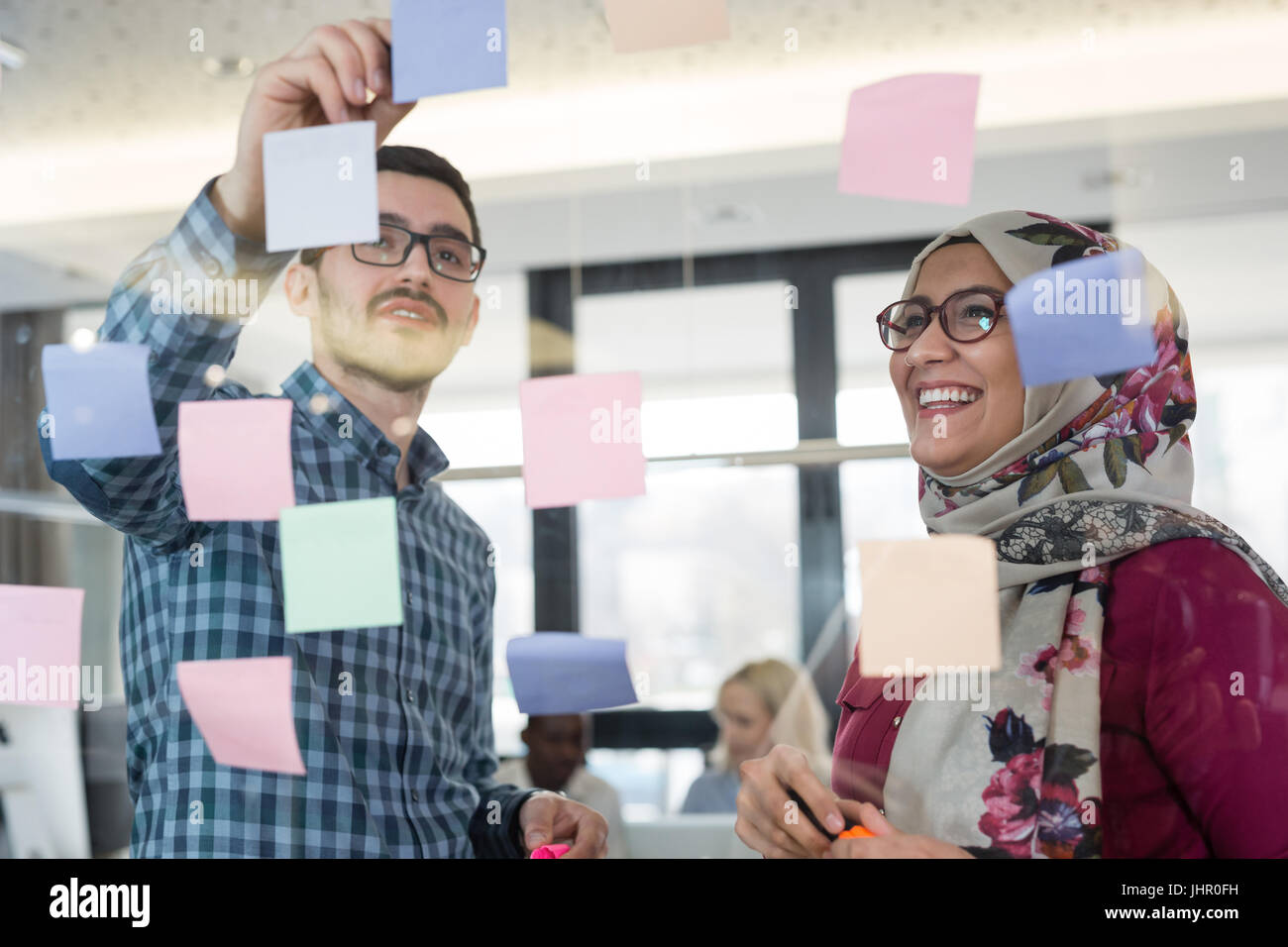 Smiling modern partners looking at sticky notes Stock Photo - Alamy