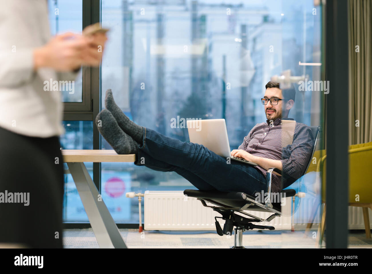 Man sitting in his office with laptop on his legs Stock Photo - Alamy