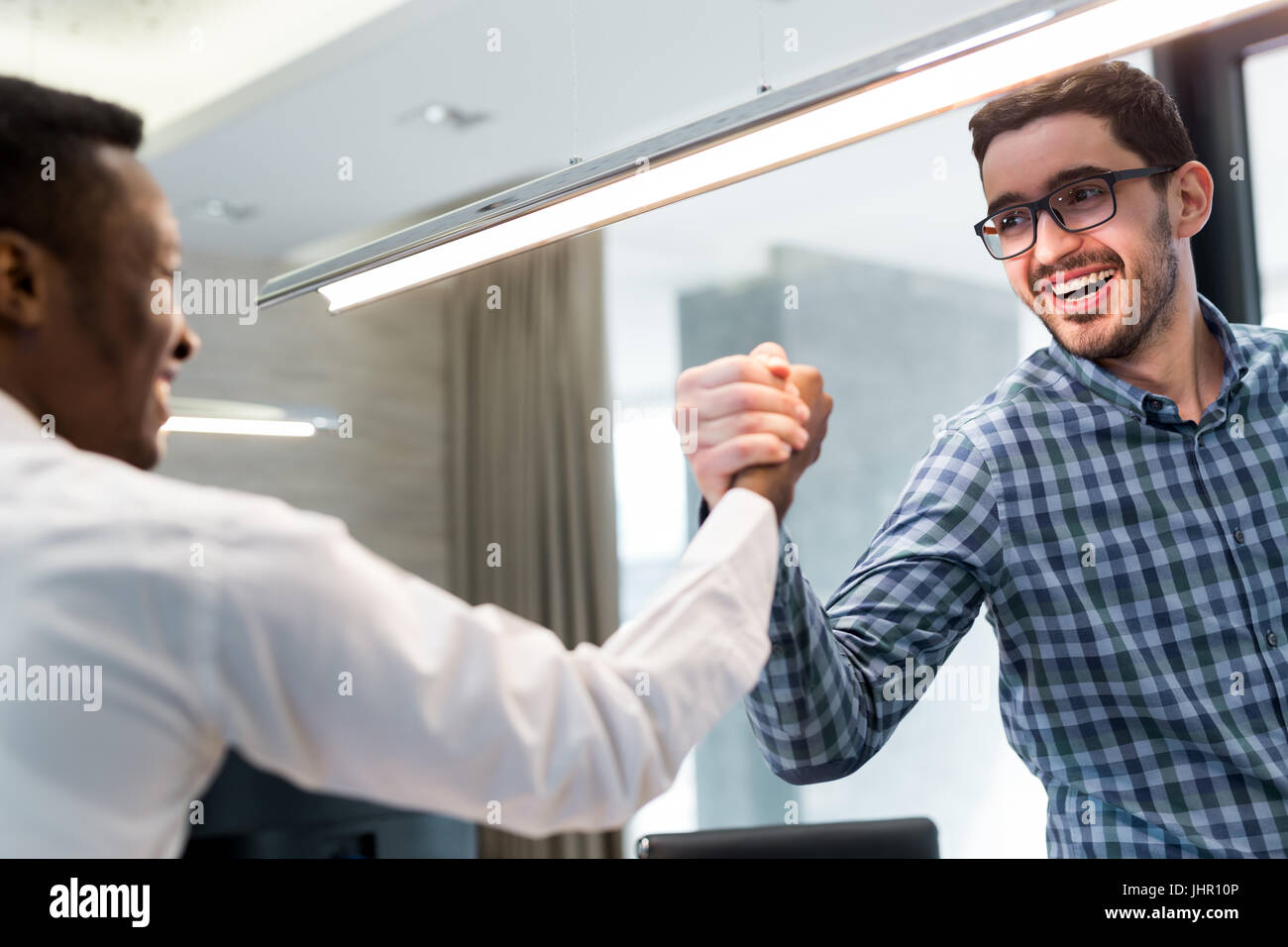 A dark or black skinned hand reaches toward a light or white skinned ...