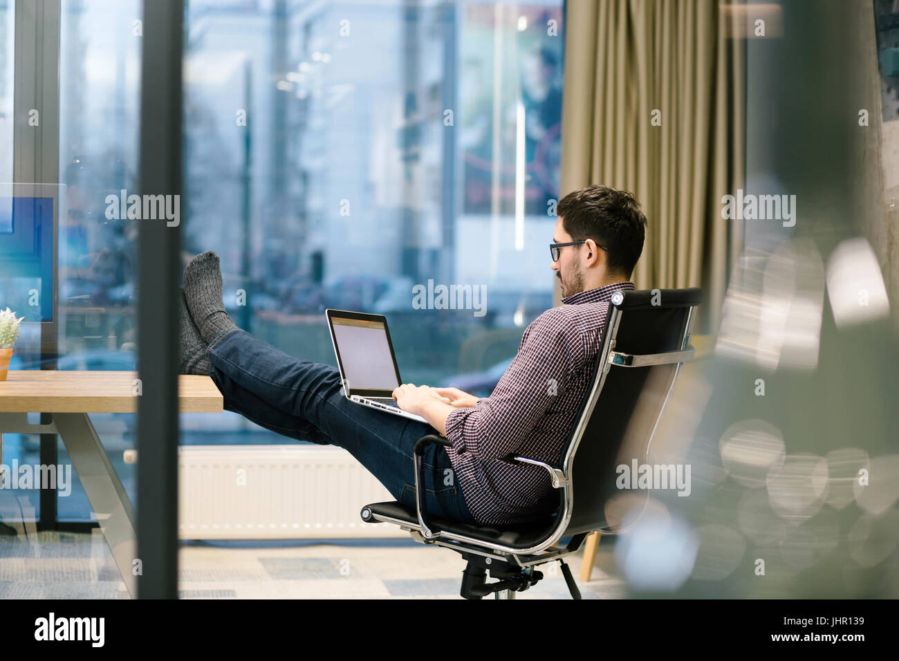 Full length side view of businessman using computer at desk in office ...