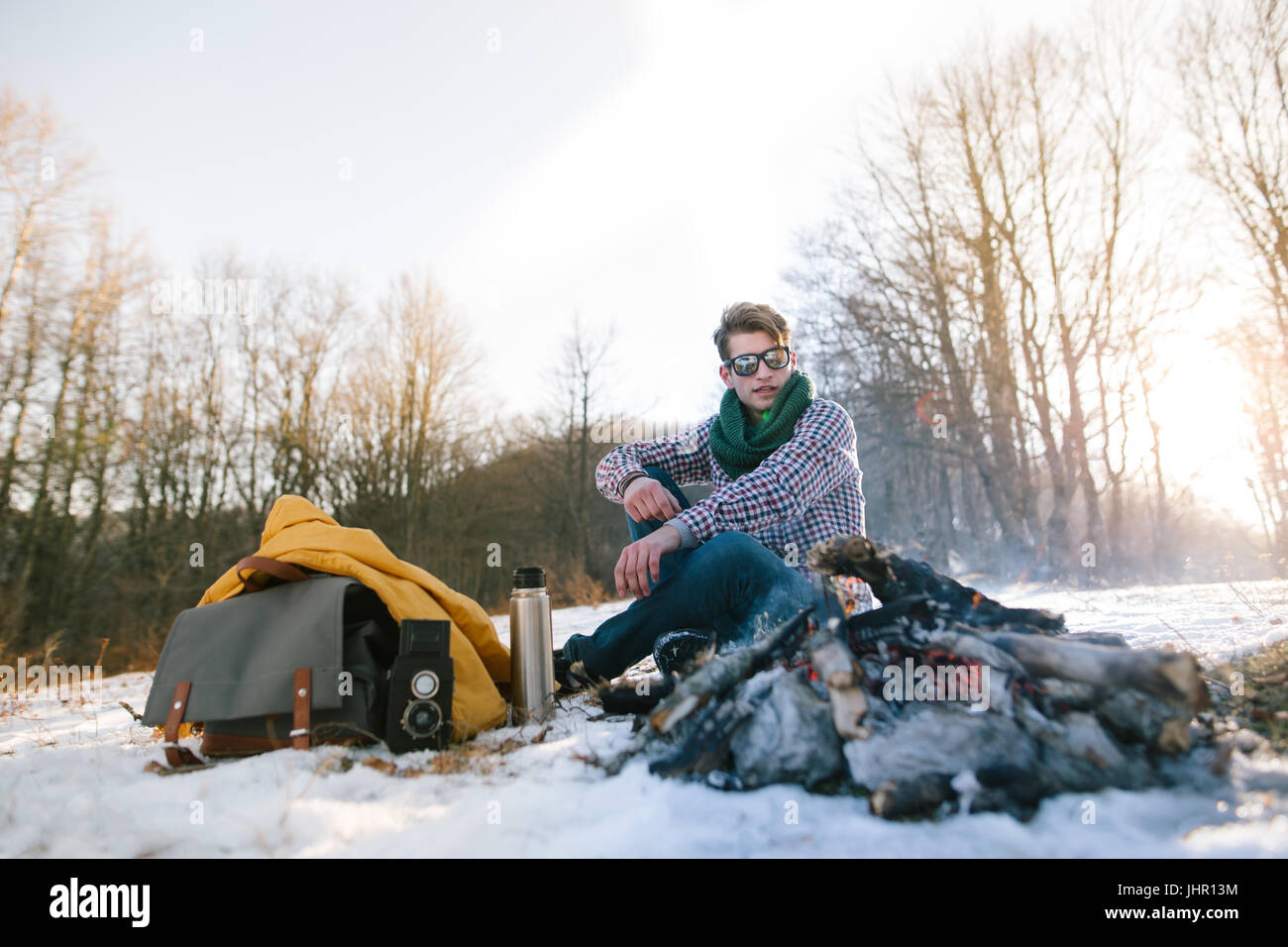 Handsome caucasian scout man warming his hands from bonfire in the ...